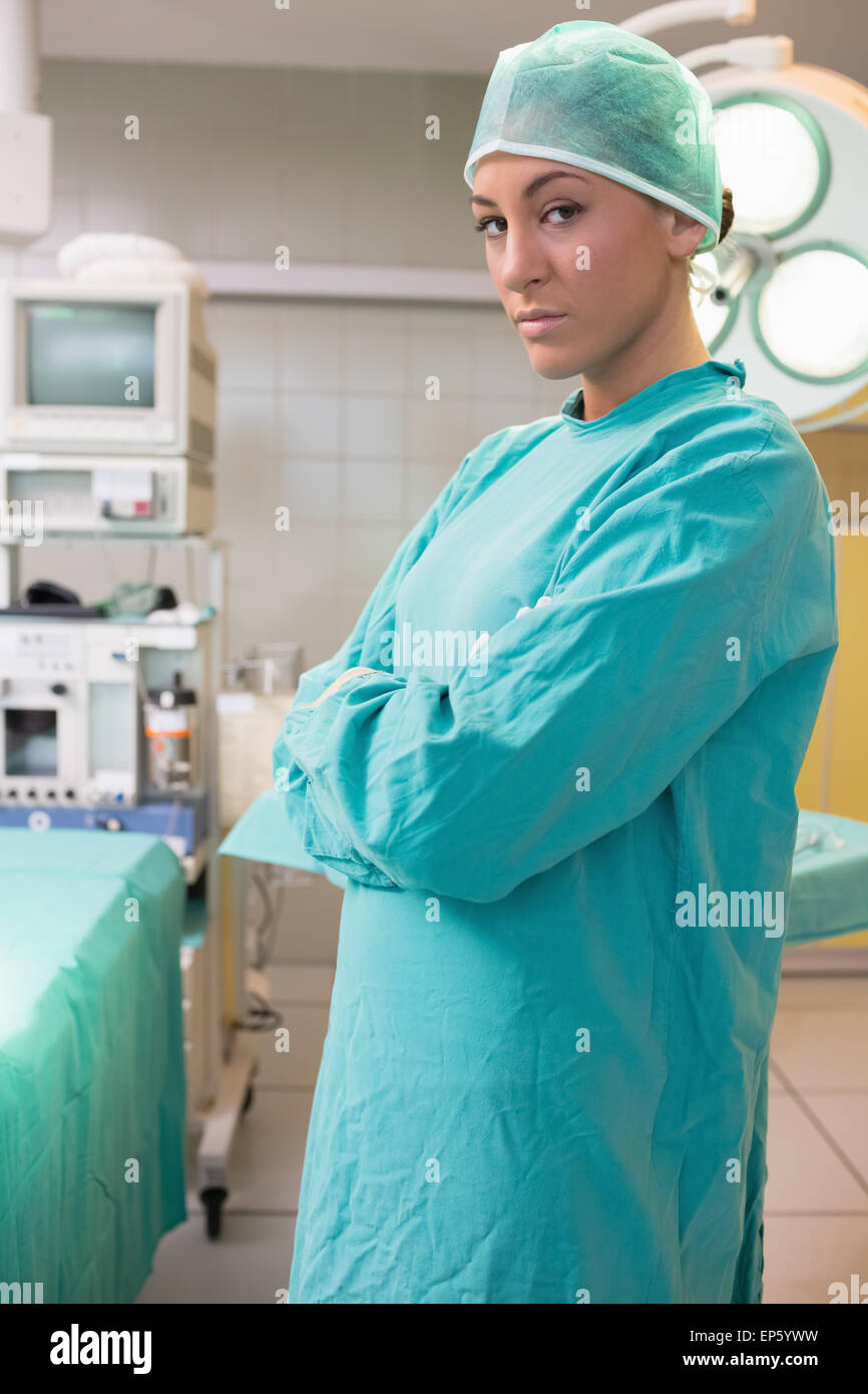 Female surgeon crossing her arms while standing next to an operating ...
