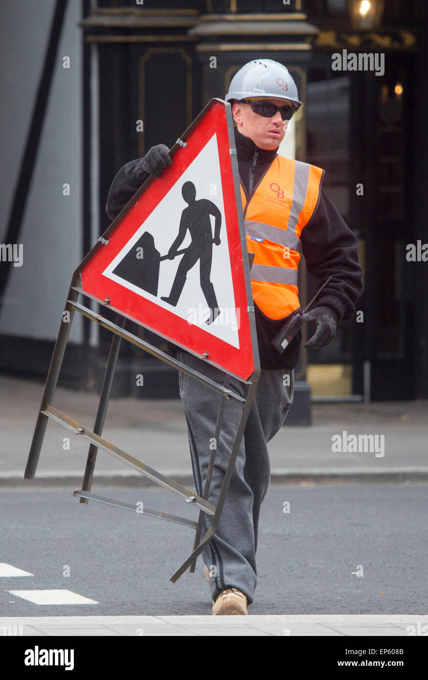 Man carrying roadworks sign workman hard hat orange Stock Photo - Alamy
