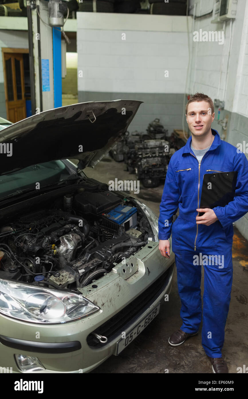 Confident mechanic standing by car with open hood Stock Photo - Alamy
