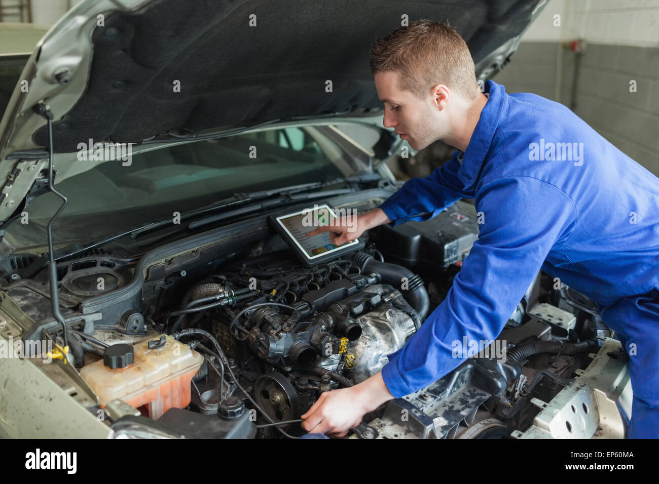 Mechanic with digital tablet repairing car engine Stock Photo - Alamy