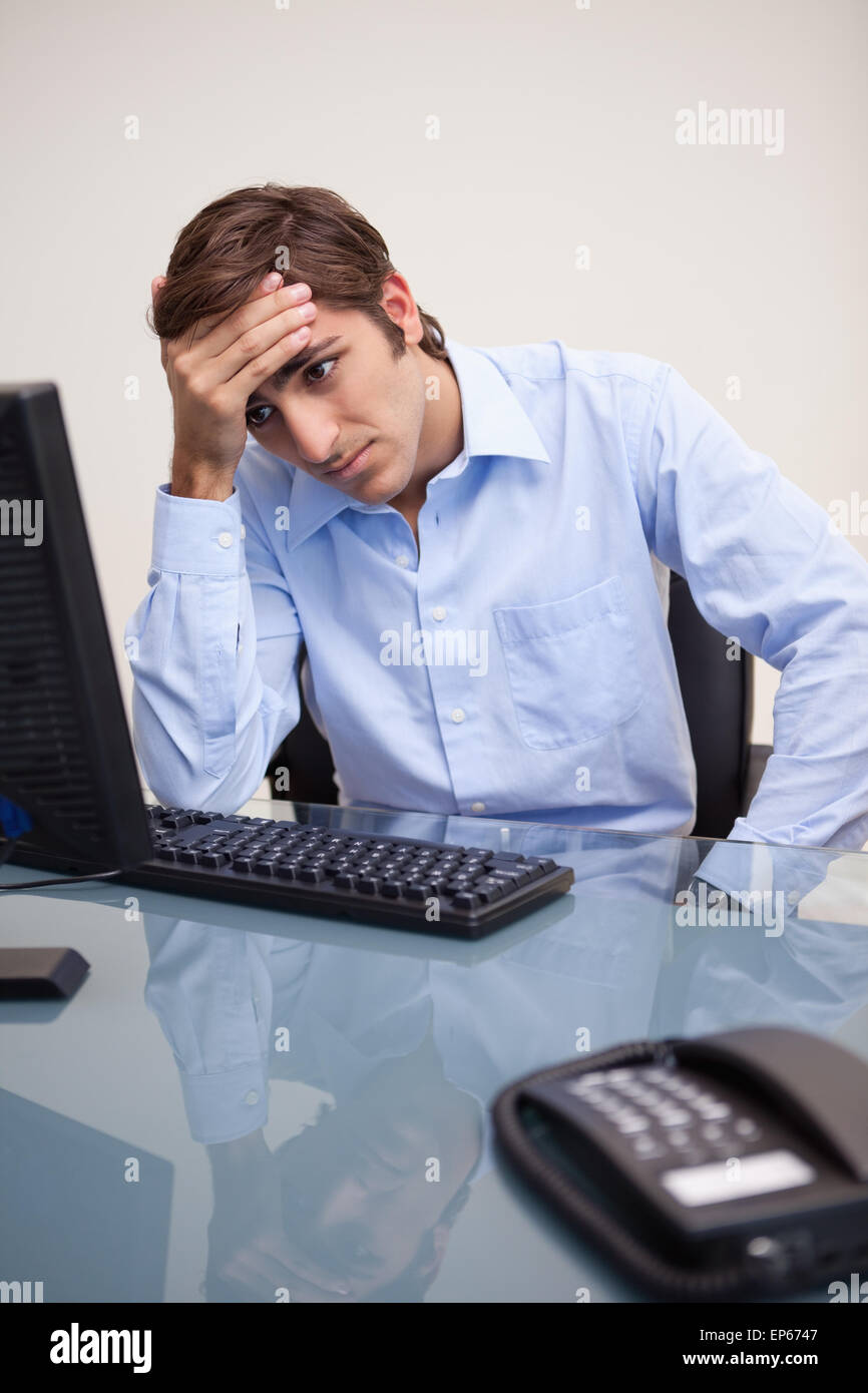 Young tense business man sitting at office desk Stock Photo - Alamy
