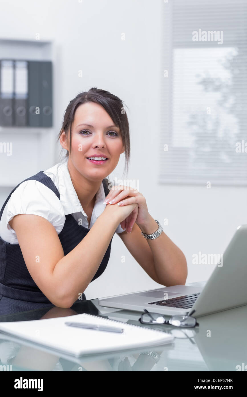 Smiling female executive sitting with laptop at desk Stock Photo - Alamy