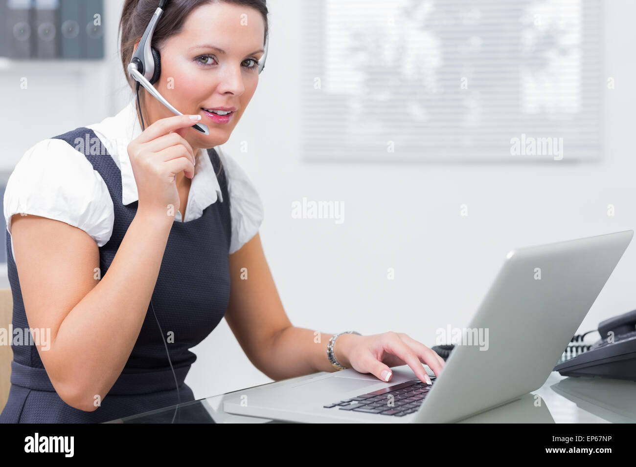 Female executive wearing headset while using laptop at desk Stock Photo ...