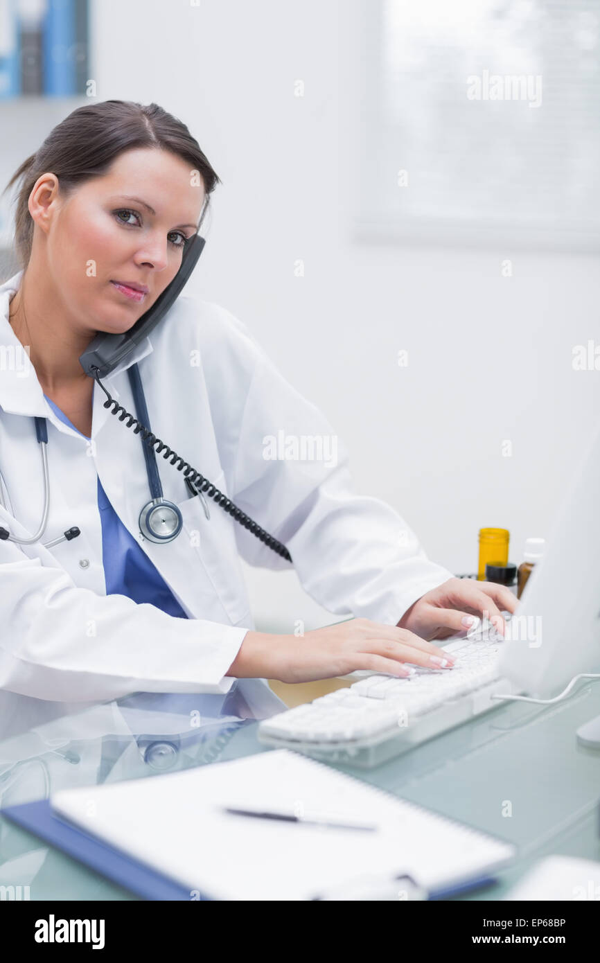 Female doctor using computer while on call at clinic Stock Photo - Alamy