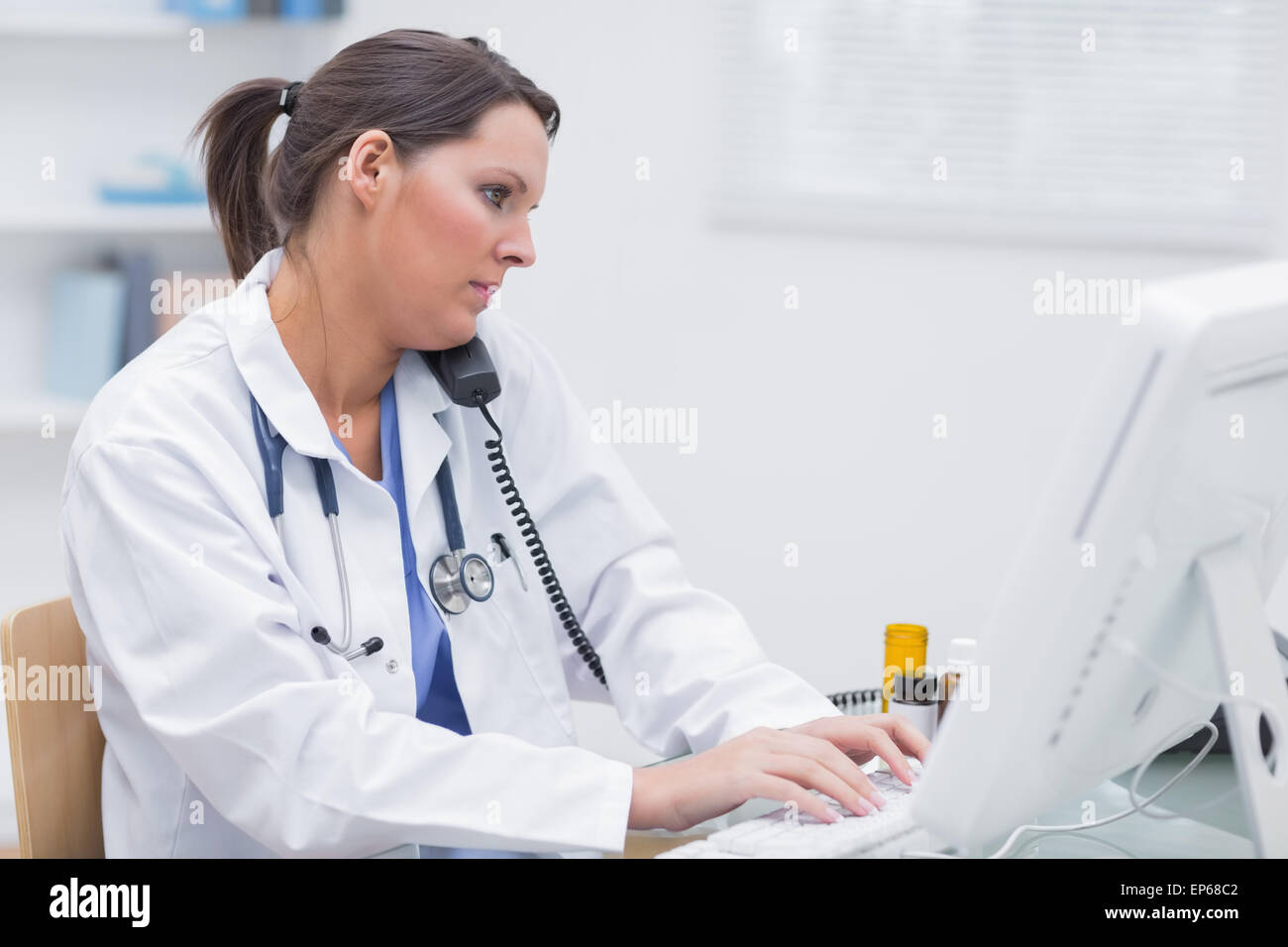 Female doctor using computer while on call at clinic Stock Photo - Alamy