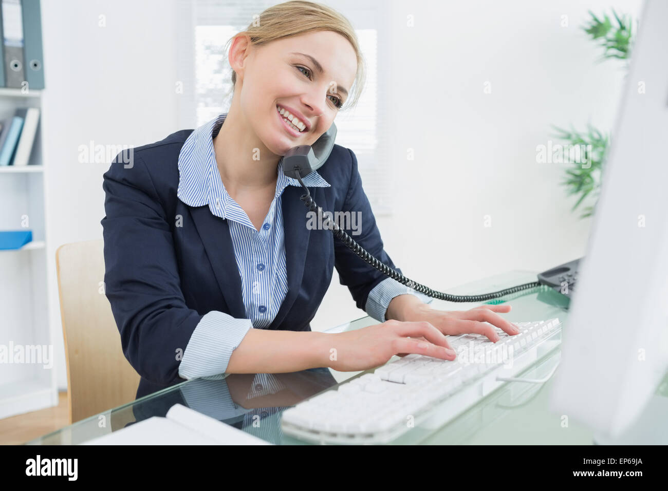 Female executive using landline phone and computer at desk Stock Photo ...