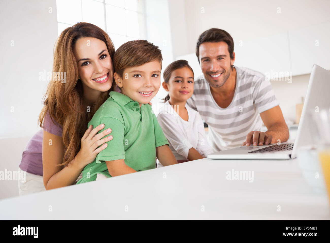 Happy family looking at the camera with a laptop Stock Photo - Alamy