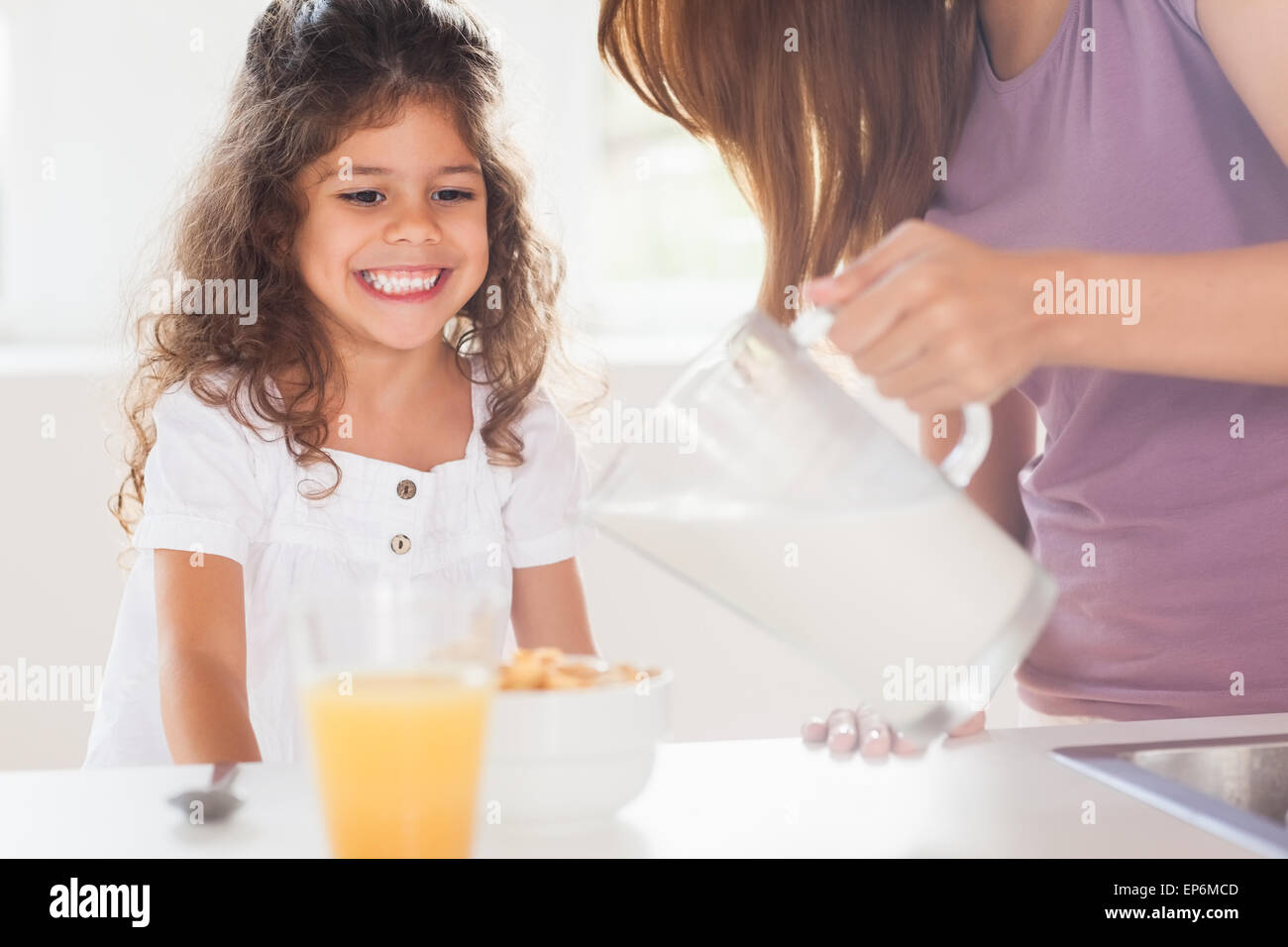 Mother putting milk in the cereal of his daughter Stock Photo - Alamy