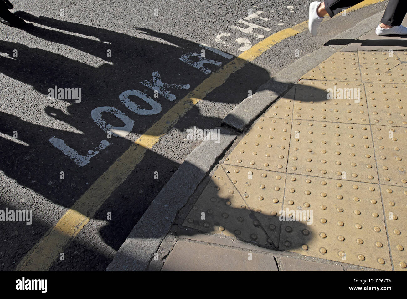 Pedestrian shadows and LOOK RIGHT sign on junction of road and pavement ...