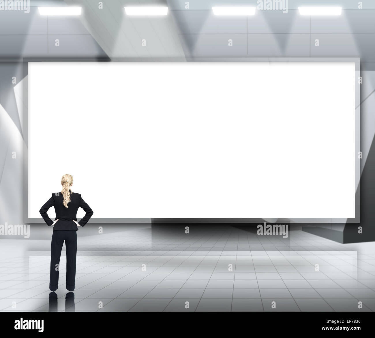 Businesswoman looking up at large blank screen under lights Stock Photo ...