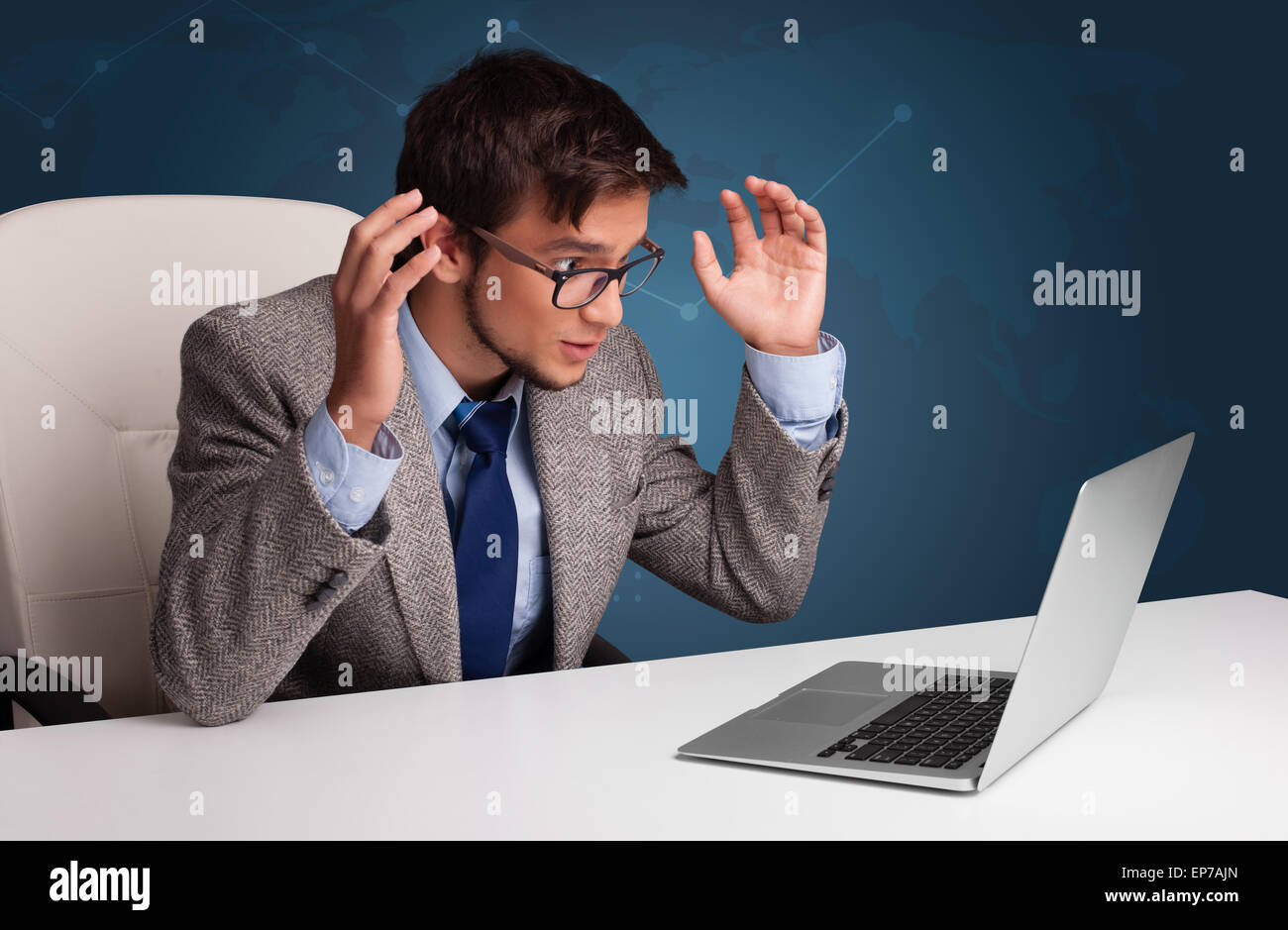 Angry man sitting at desk and typing on laptop Stock Photo - Alamy