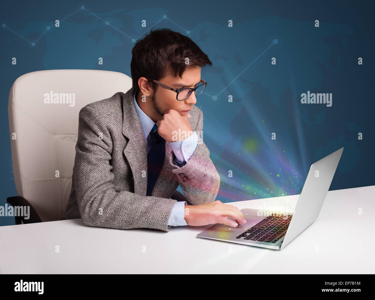 Handsome man sitting at desk and typing on laptop with abstract lights ...