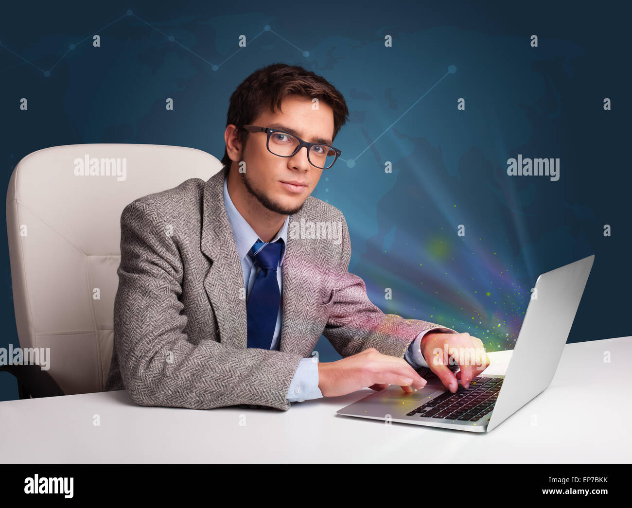 Handsome man sitting at desk and typing on laptop with abstract lights ...