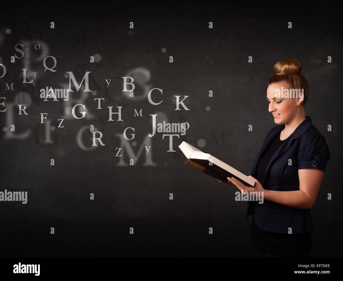 Young lady reading a book with alphabet letters Stock Photo - Alamy