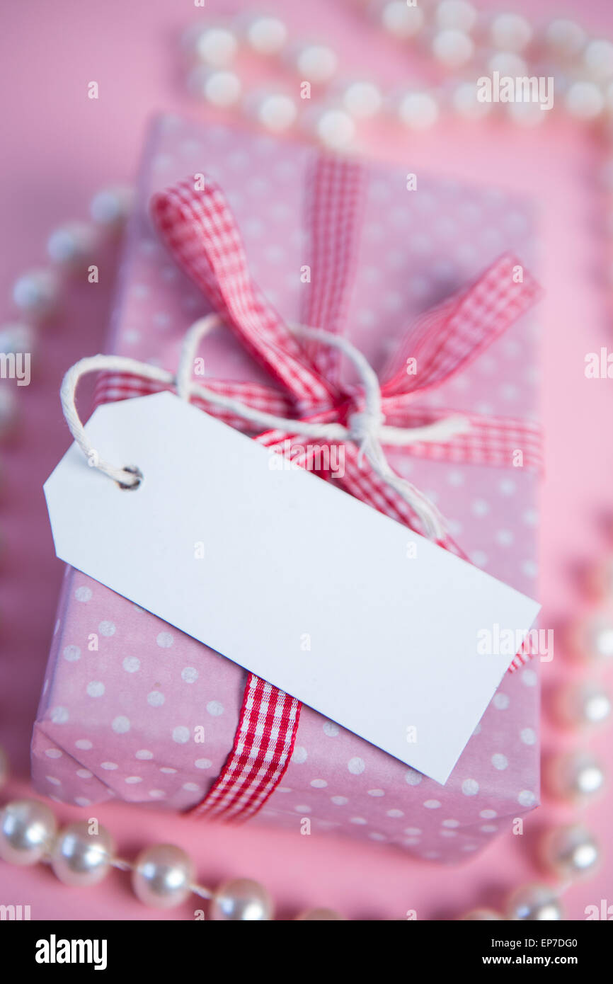 Pink gift wrapped box with blank tag and pearls Stock Photo - Alamy