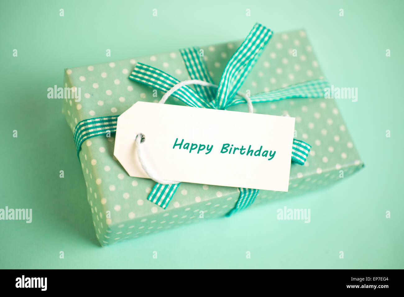 Pretty green gift with a happy birthday card on a green background ...