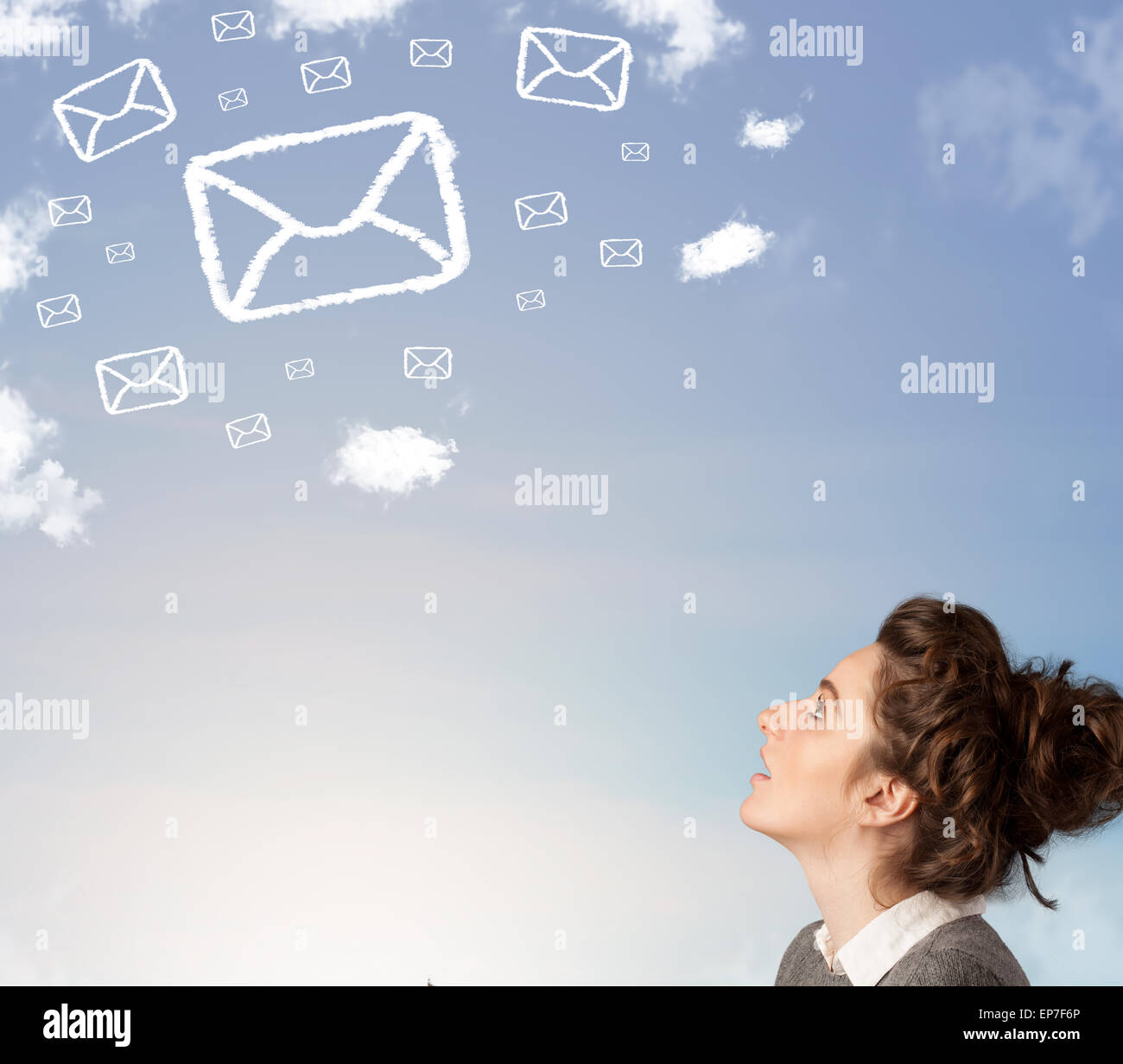 Young girl looking at mail symbol clouds on blue sky Stock Photo - Alamy
