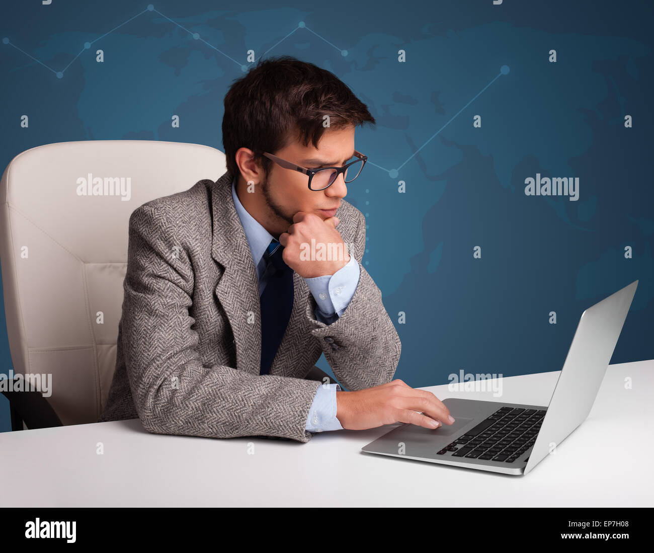 Young man sitting at desk and typing on laptop Stock Photo - Alamy