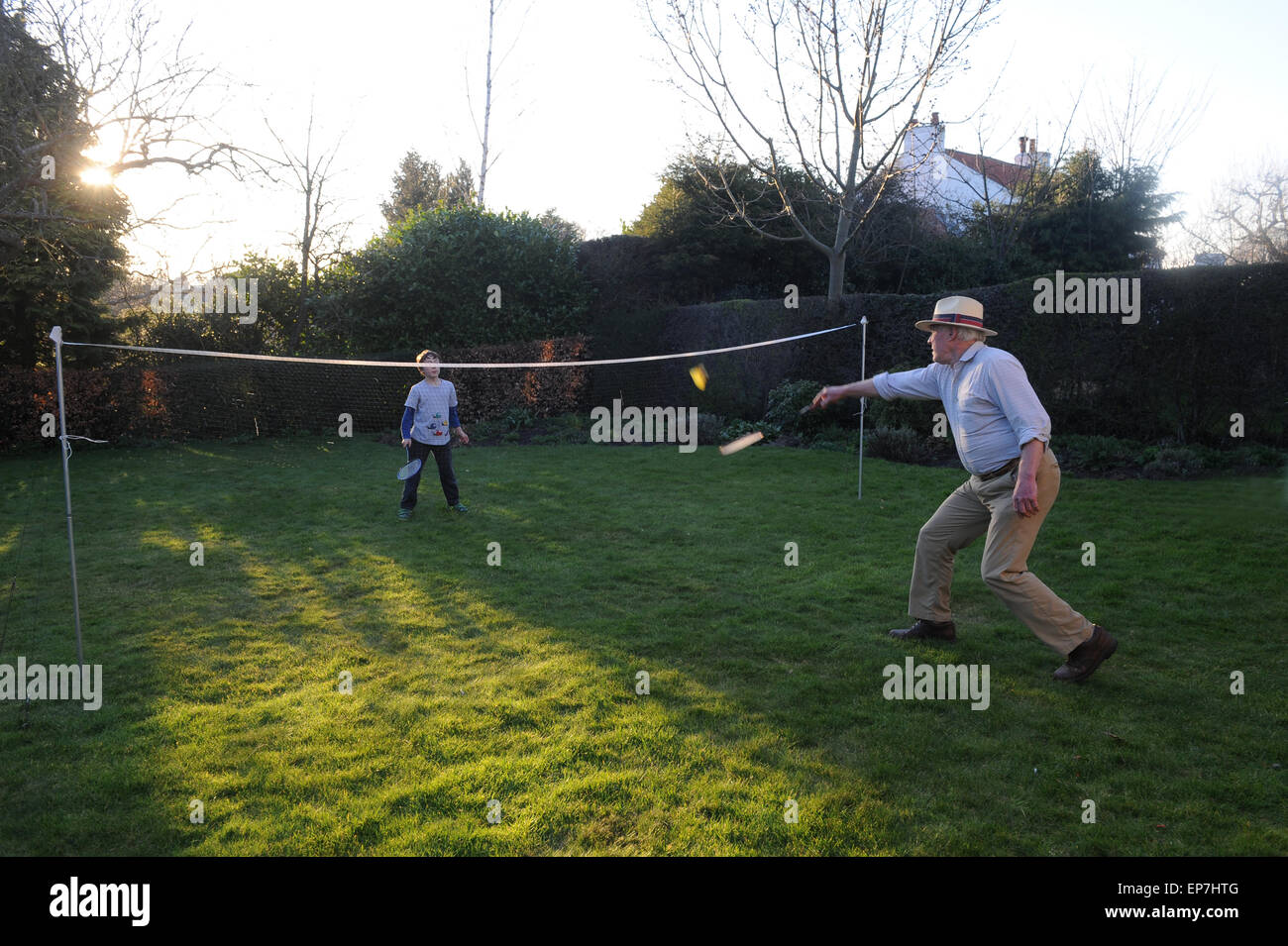 Grandfather and grandson playing badminton together in the garden in ...
