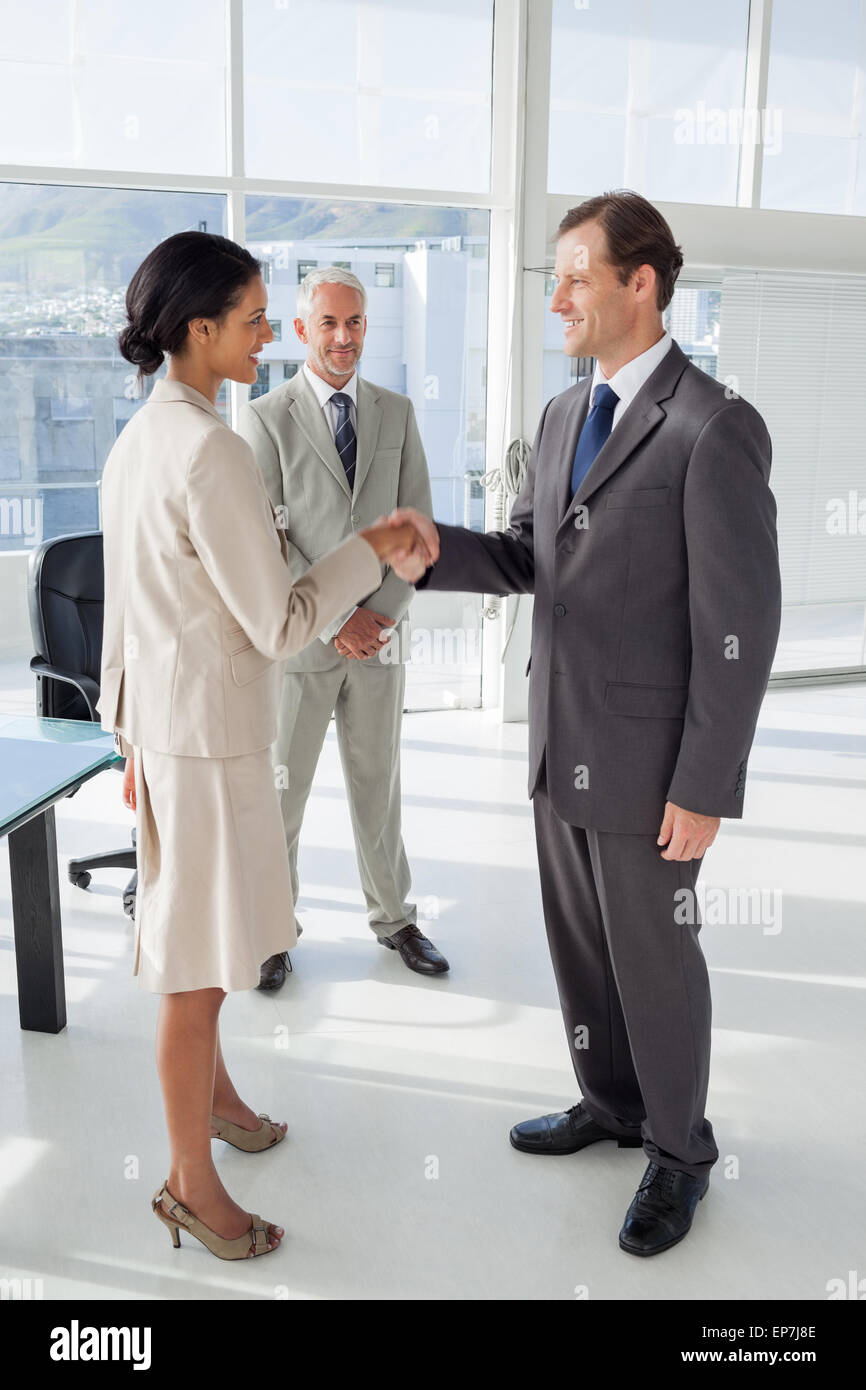 Two people shaking their hands with colleague watching them Stock Photo ...