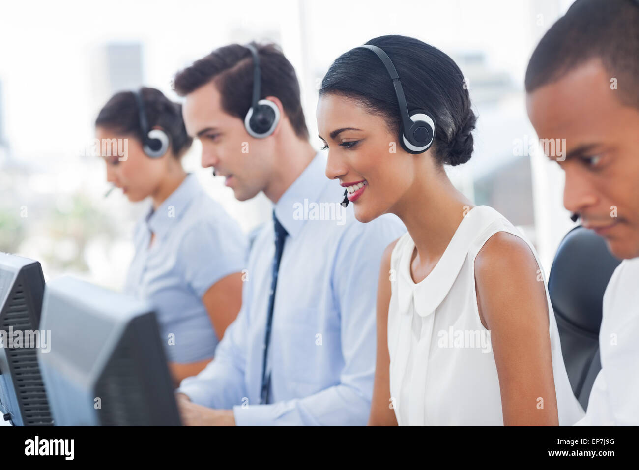 Smiling call center employees sitting in line Stock Photo - Alamy