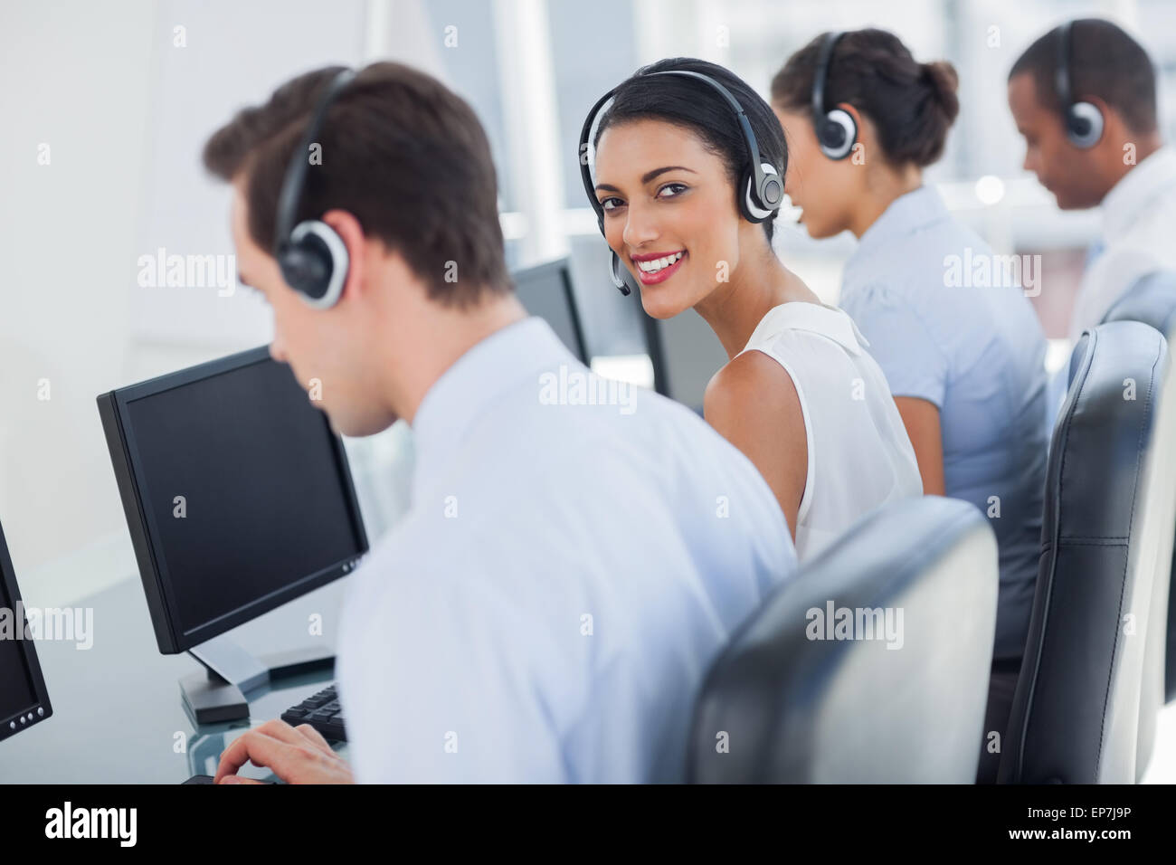Smiling call centre employee looking over shoulder Stock Photo - Alamy