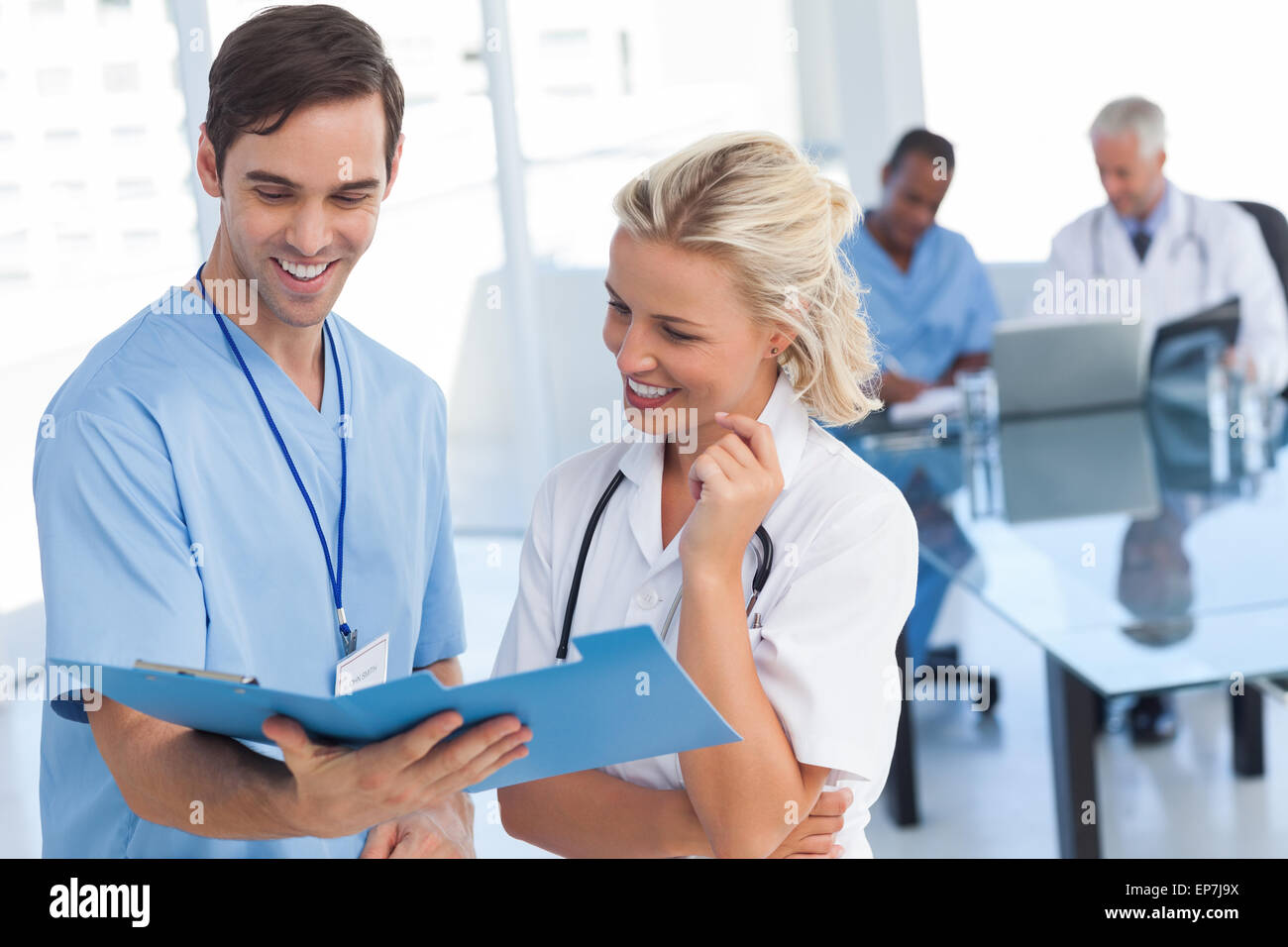Two smiling doctors talking about a blue file Stock Photo - Alamy