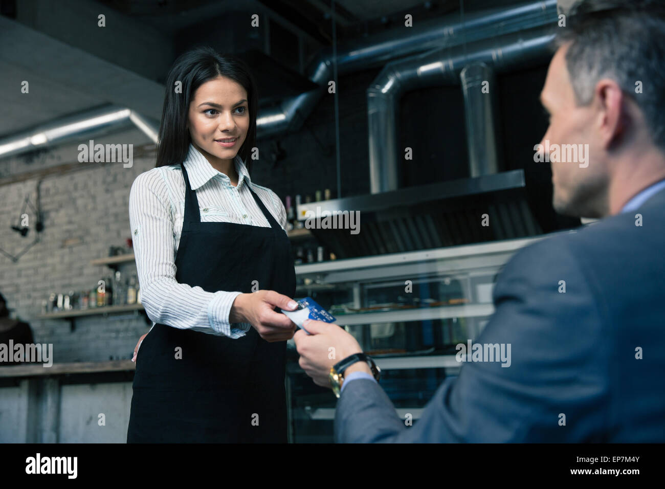 Man giving bank card to female waiter in restaurant Stock Photo - Alamy
