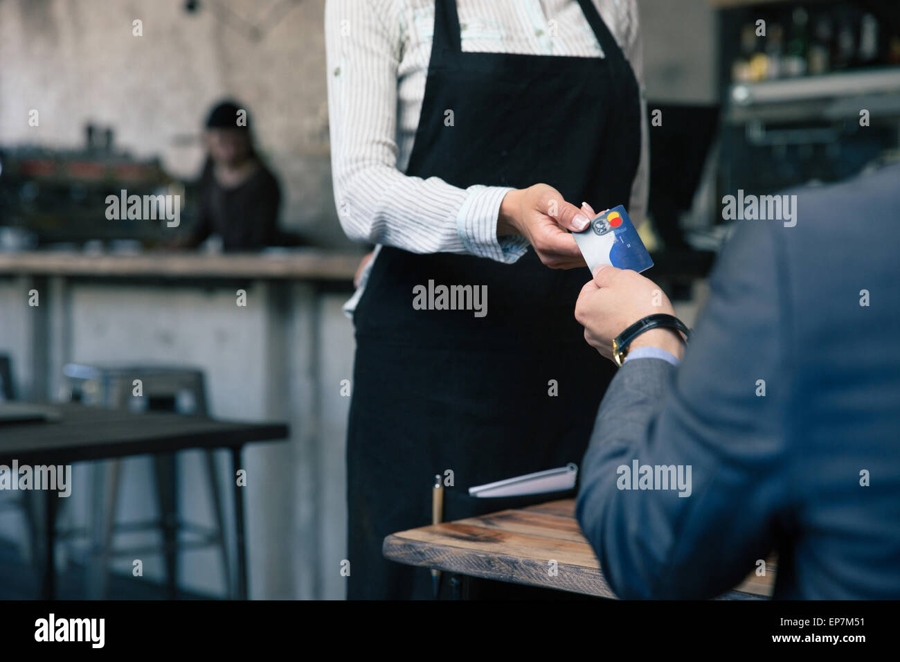 Closeup image of a man giving credit card to waiter in cafe Stock Photo ...