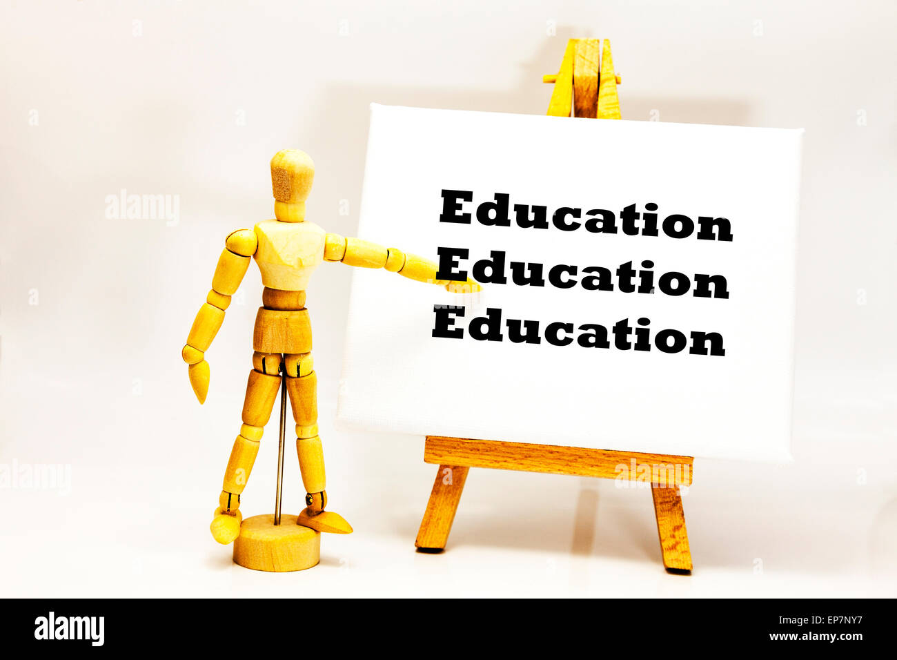 Wooden man with white board pointing at words "Education" school ...