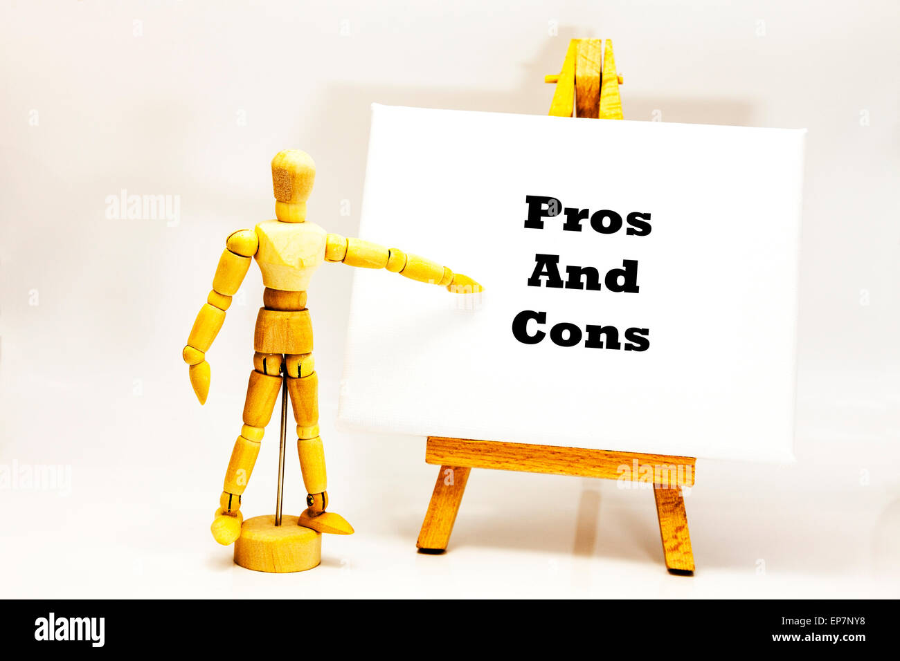 Wooden man with white board pointing at words "Pros And Cons" for ...