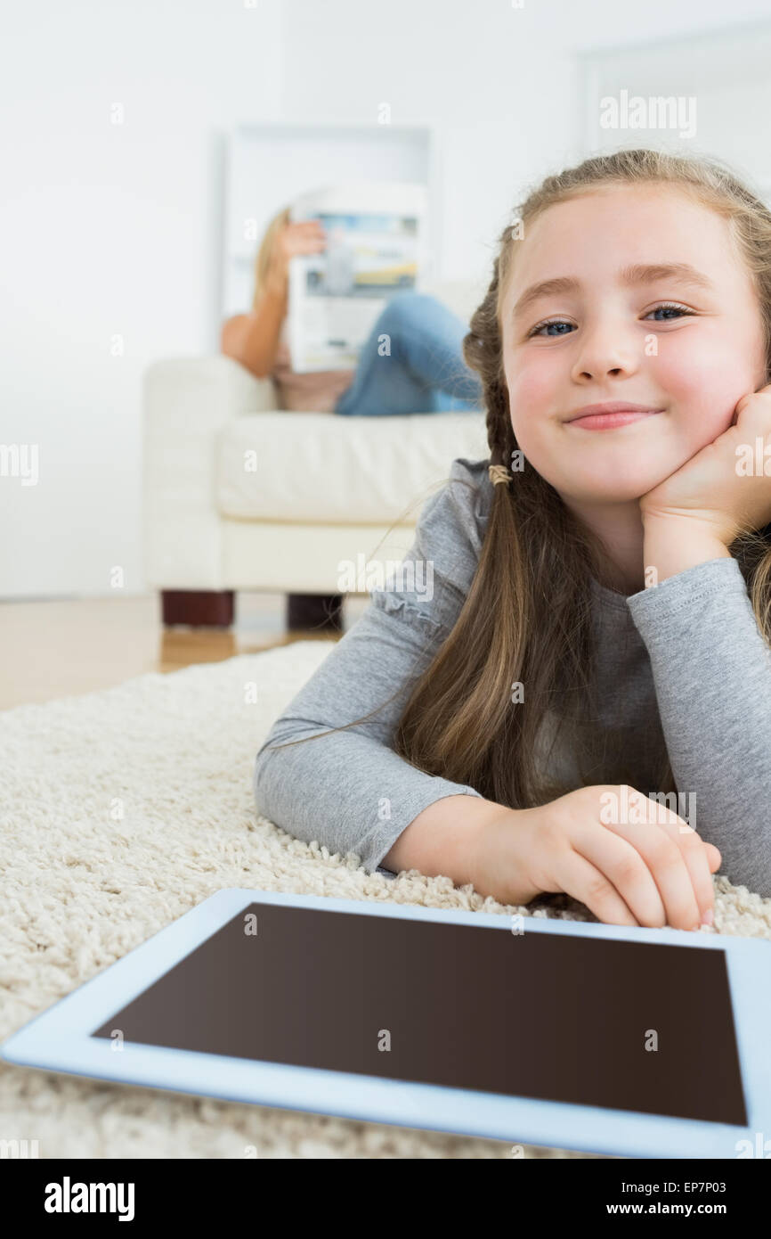 Happy girl with her tablet pc and her mother reading newspaper Stock ...