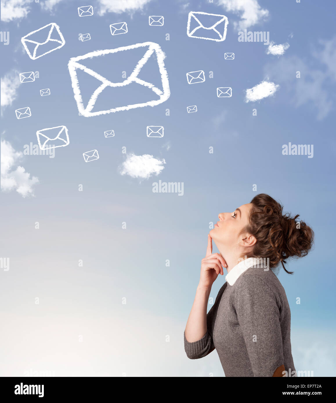 Young girl looking at mail symbol clouds on blue sky Stock Photo - Alamy