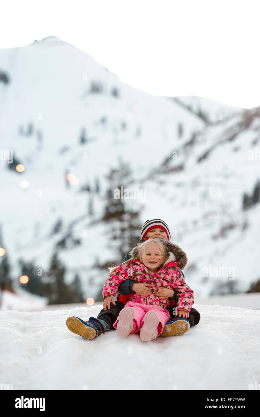 Cute young children sliding down a snow slide together in the kid's ...