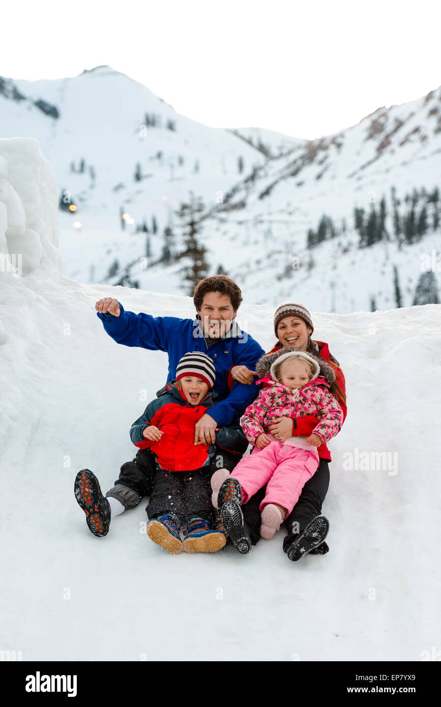 Laughing family slides down snow slide with his young daughter at Squaw ...