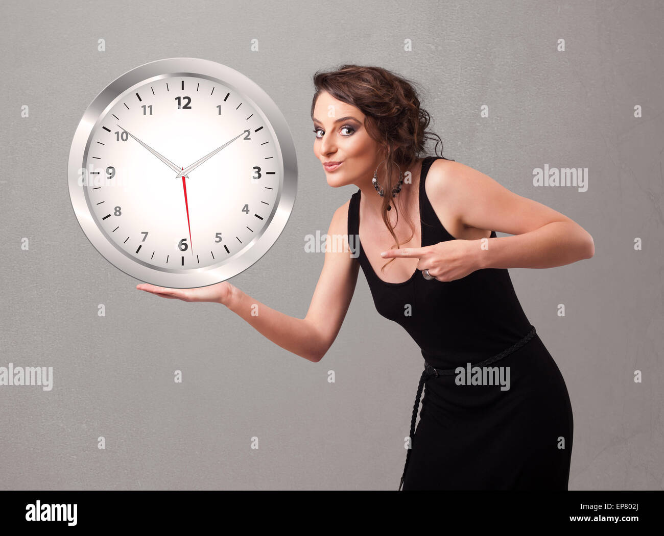 Attractive lady holding a huge clock Stock Photo - Alamy