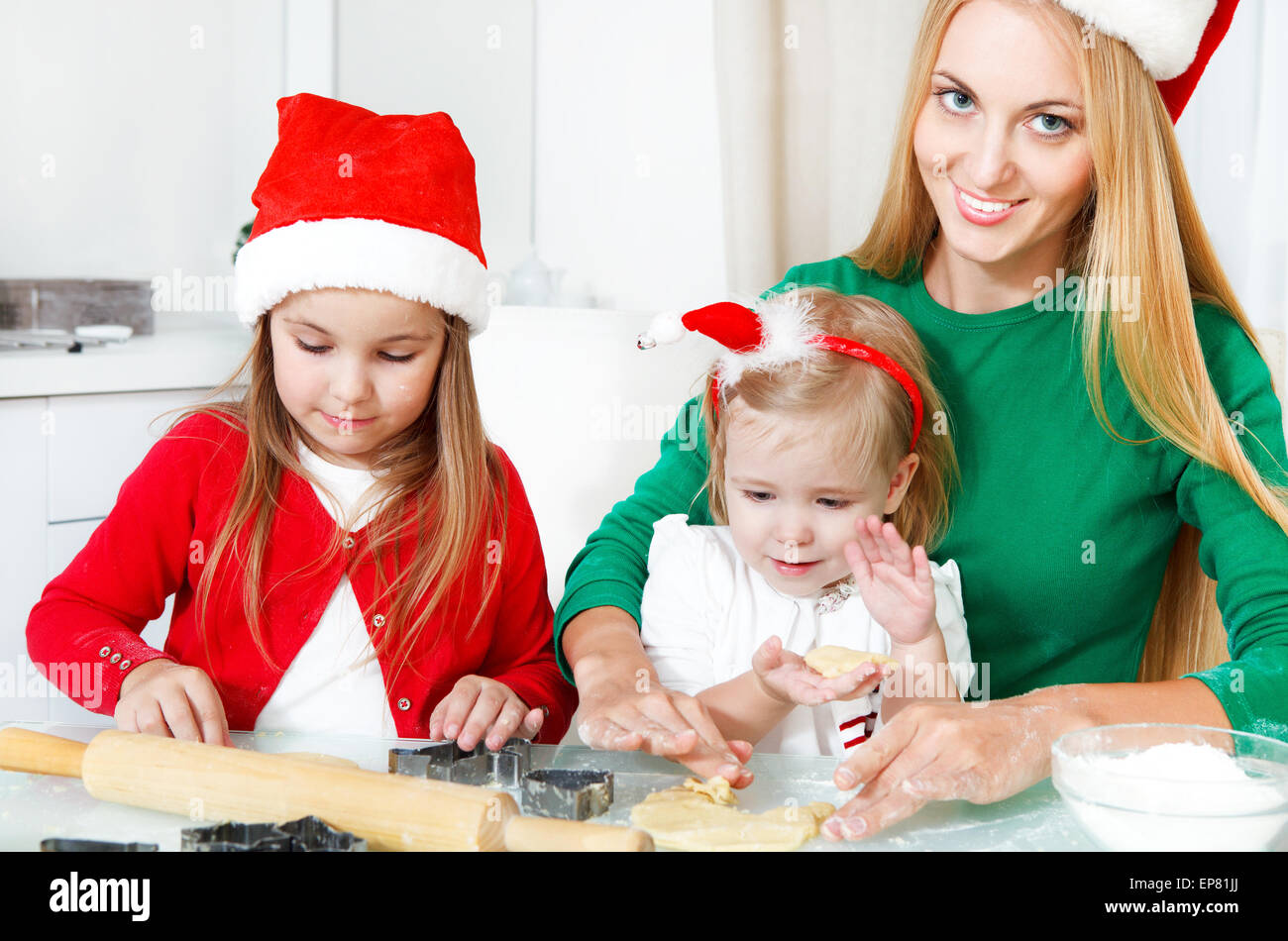 Adorable girls with her mother baking Christmas cookies in the kitchen ...