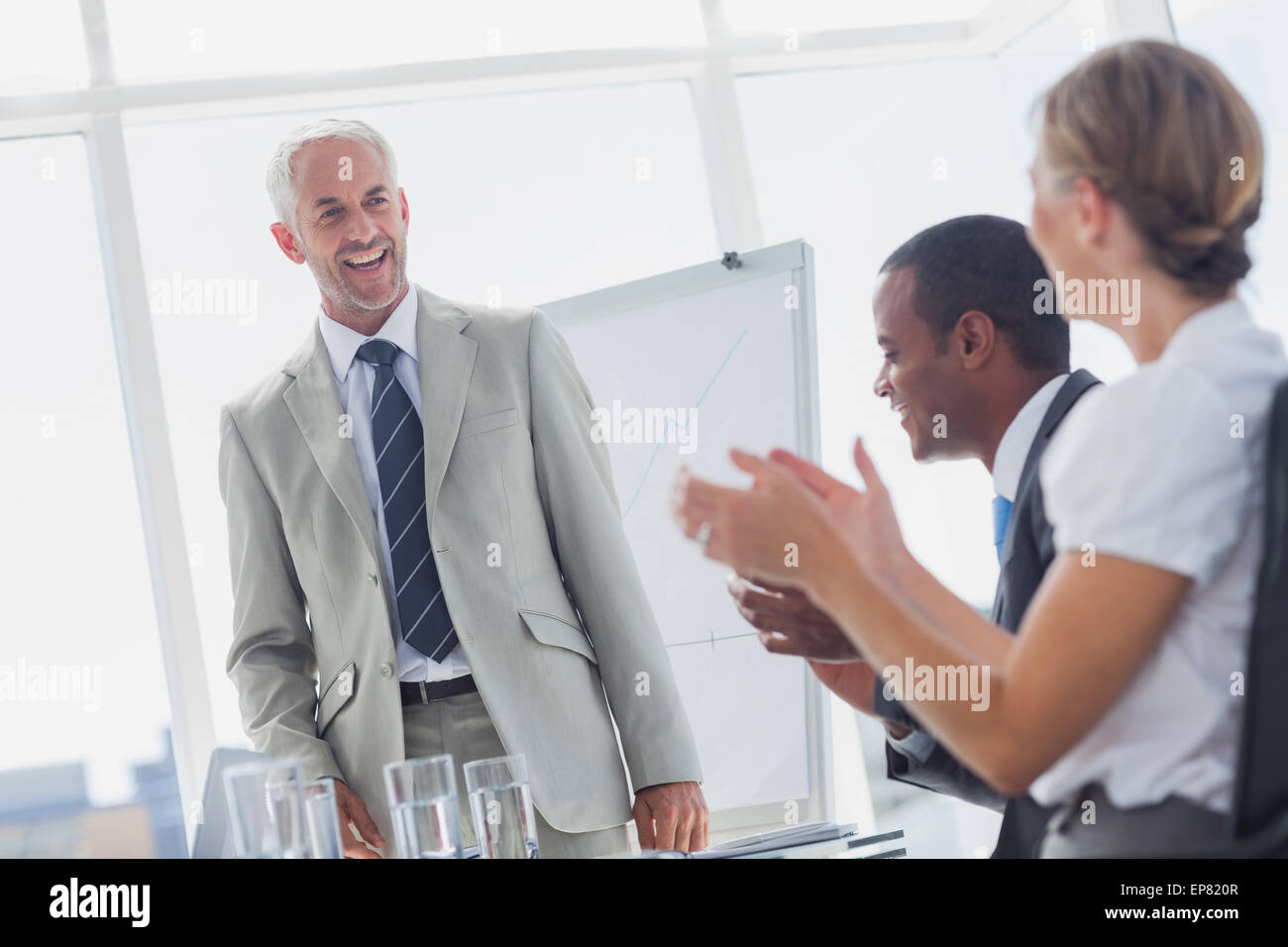 Colleagues applauding smiling manager during a meeting Stock Photo - Alamy