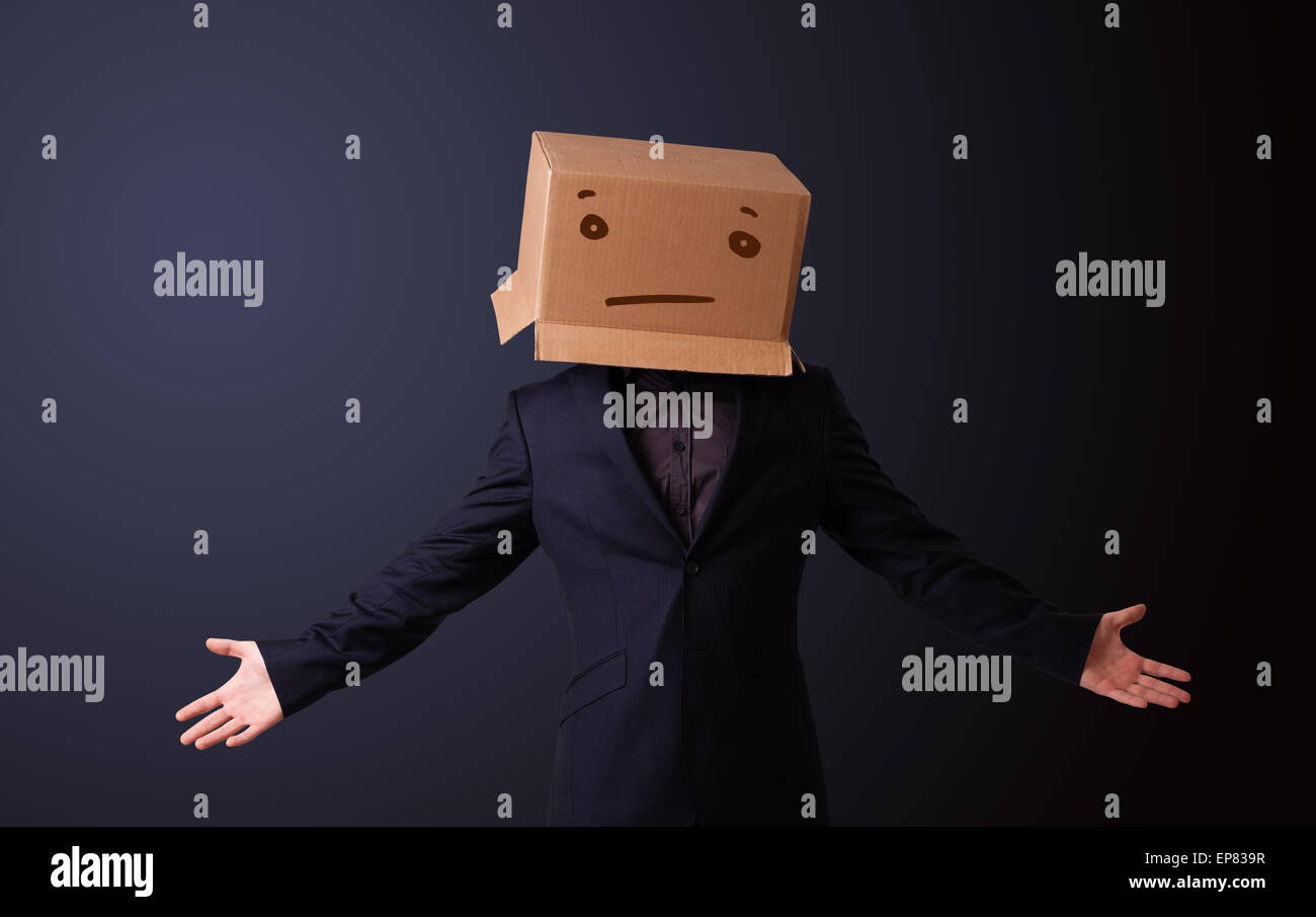 Young man gesturing with a cardboard box on his head with straight face ...