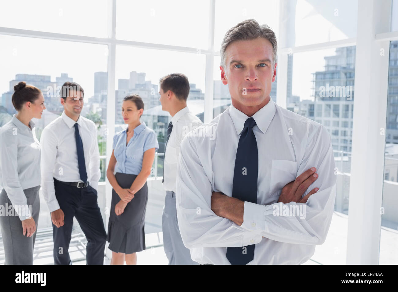 Boss with arms folded standing in a modern office Stock Photo - Alamy