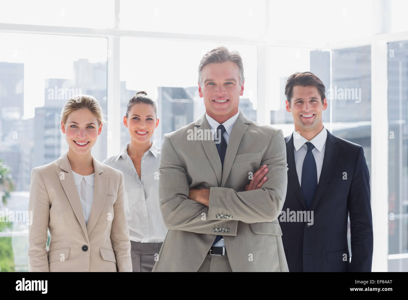 Boss with his arms folded standing with smiling colleagues behind Stock ...