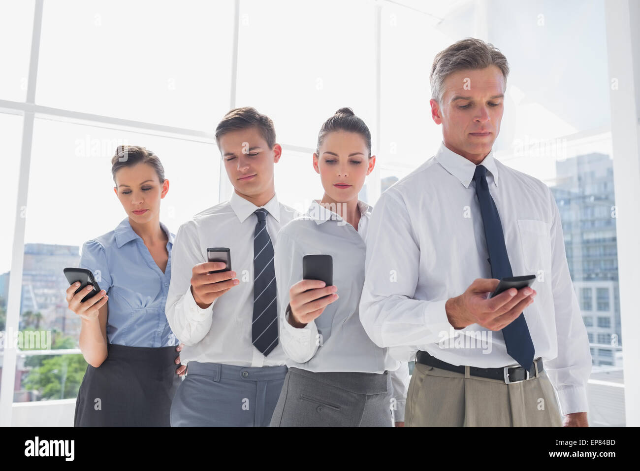 Team of business people standing together in line with their mobile ...