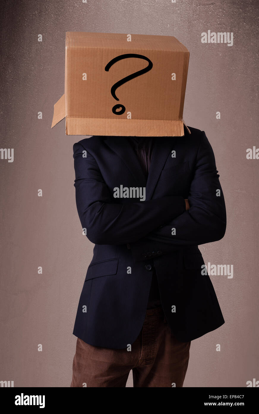 Young man gesturing with a cardboard box on his head with question mark ...