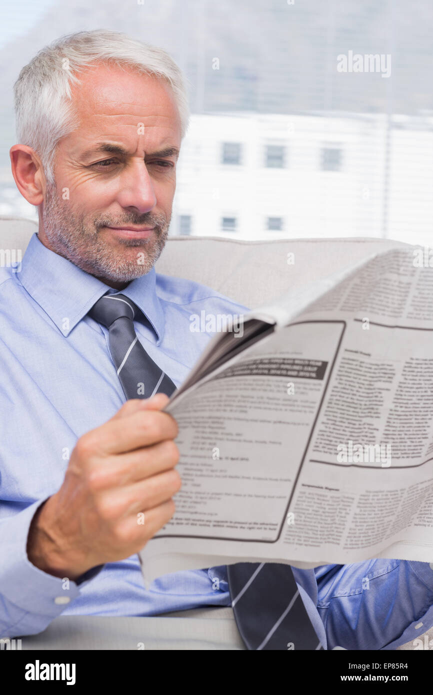 Attractive businessman reading a newspaper on couch Stock Photo - Alamy