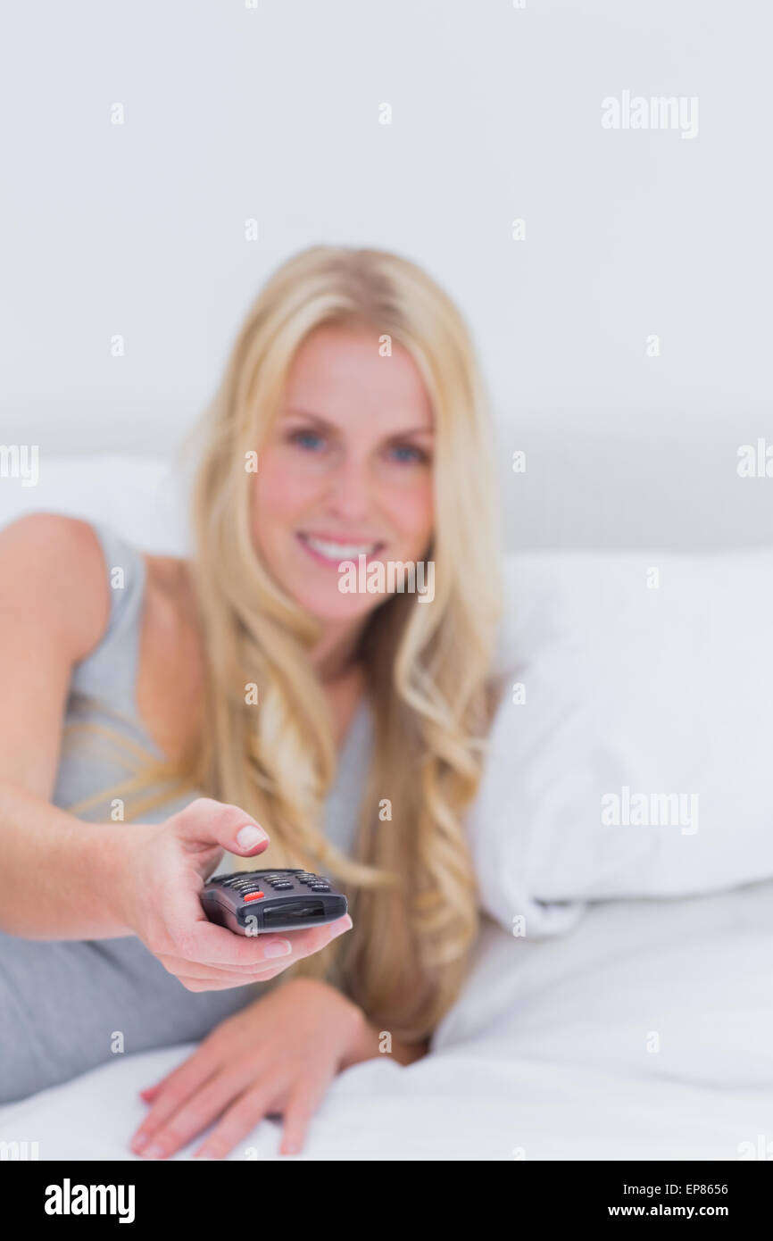 Blonde woman pointing the remote control at the camera Stock Photo - Alamy