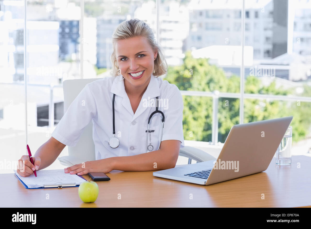 Beautiful nurse writing on a notepad on her desk Stock Photo - Alamy