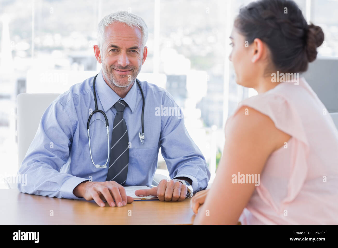 Attractive doctor sitting in front of patient Stock Photo - Alamy