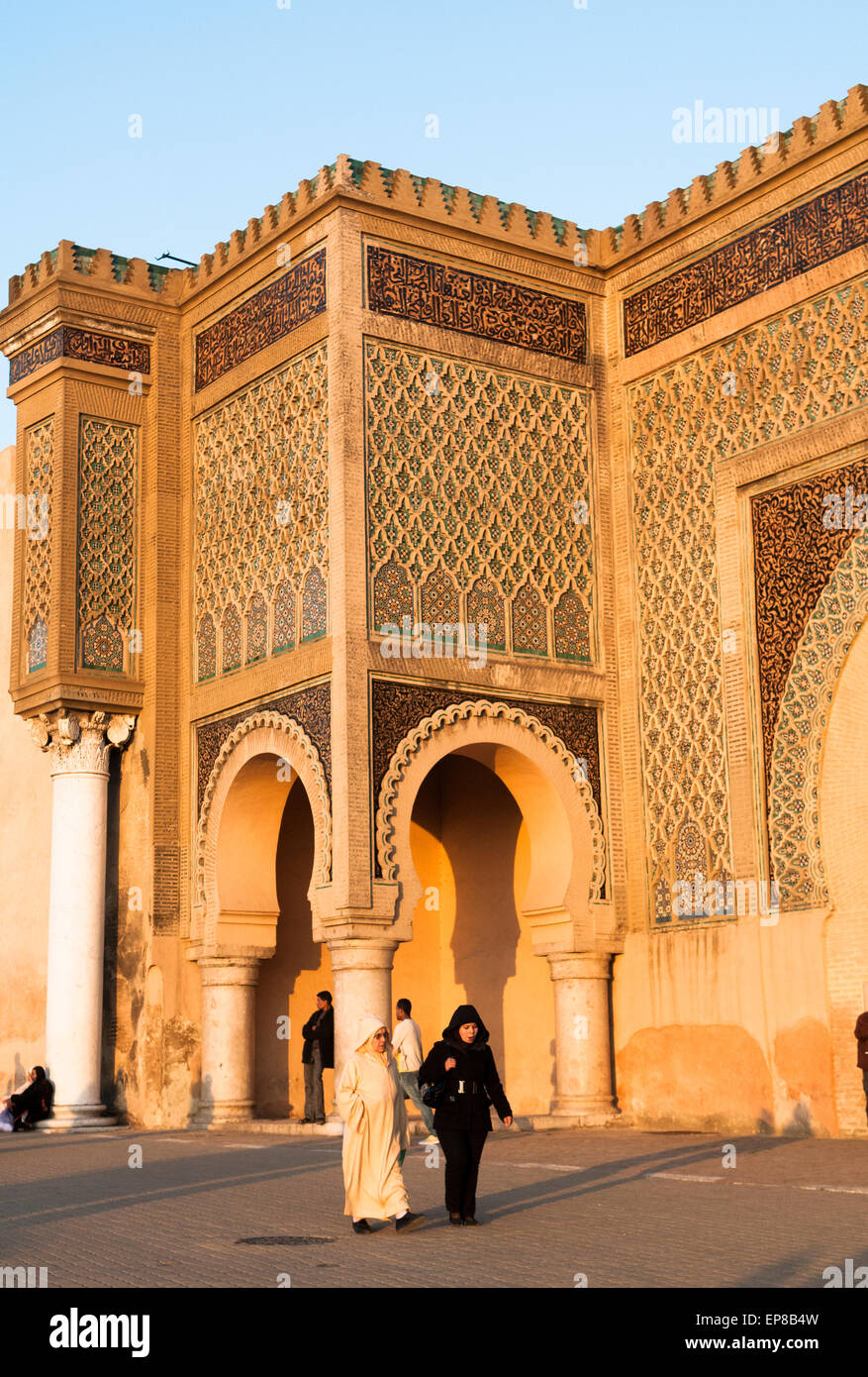 Local women walking by the beautiful Bab Mansour in the old city wall ...