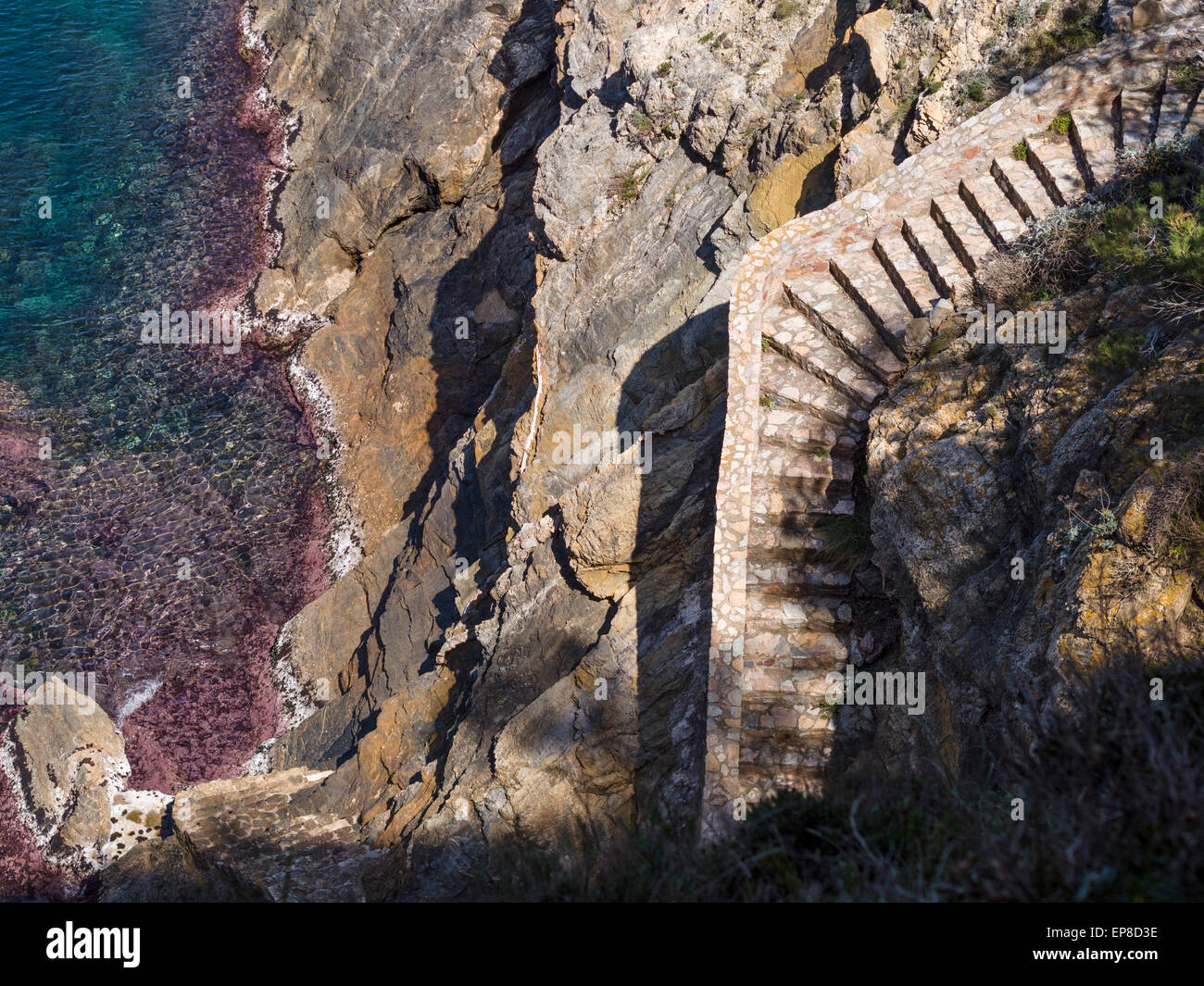 A stone stair winds down the cliff from the Cami de Ronda path. A stone ...