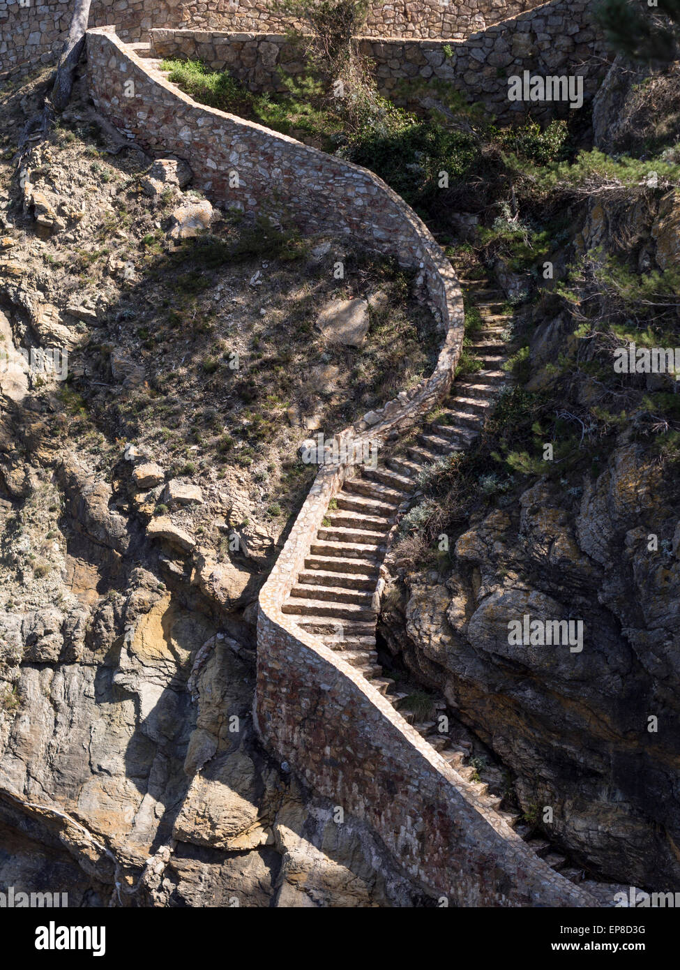 A stone stair winds down the cliff from the Cami de Ronda path. A stone ...